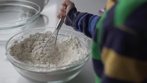 Close-up shot of a boy mixing flour in bowl at home, Cherry Hill, New ...