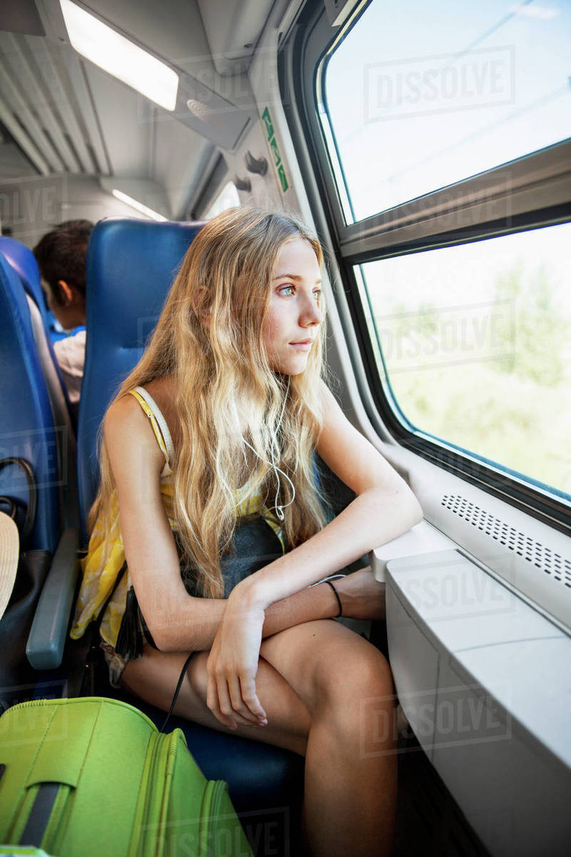 Young woman looking through window in train - Stock Photo - Dissolve