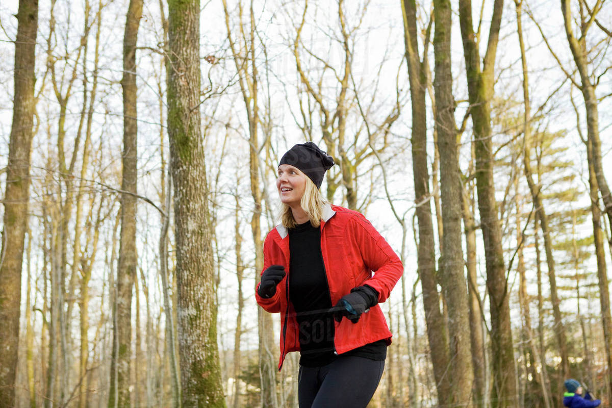 Woman running through forest - Stock Photo - Dissolve