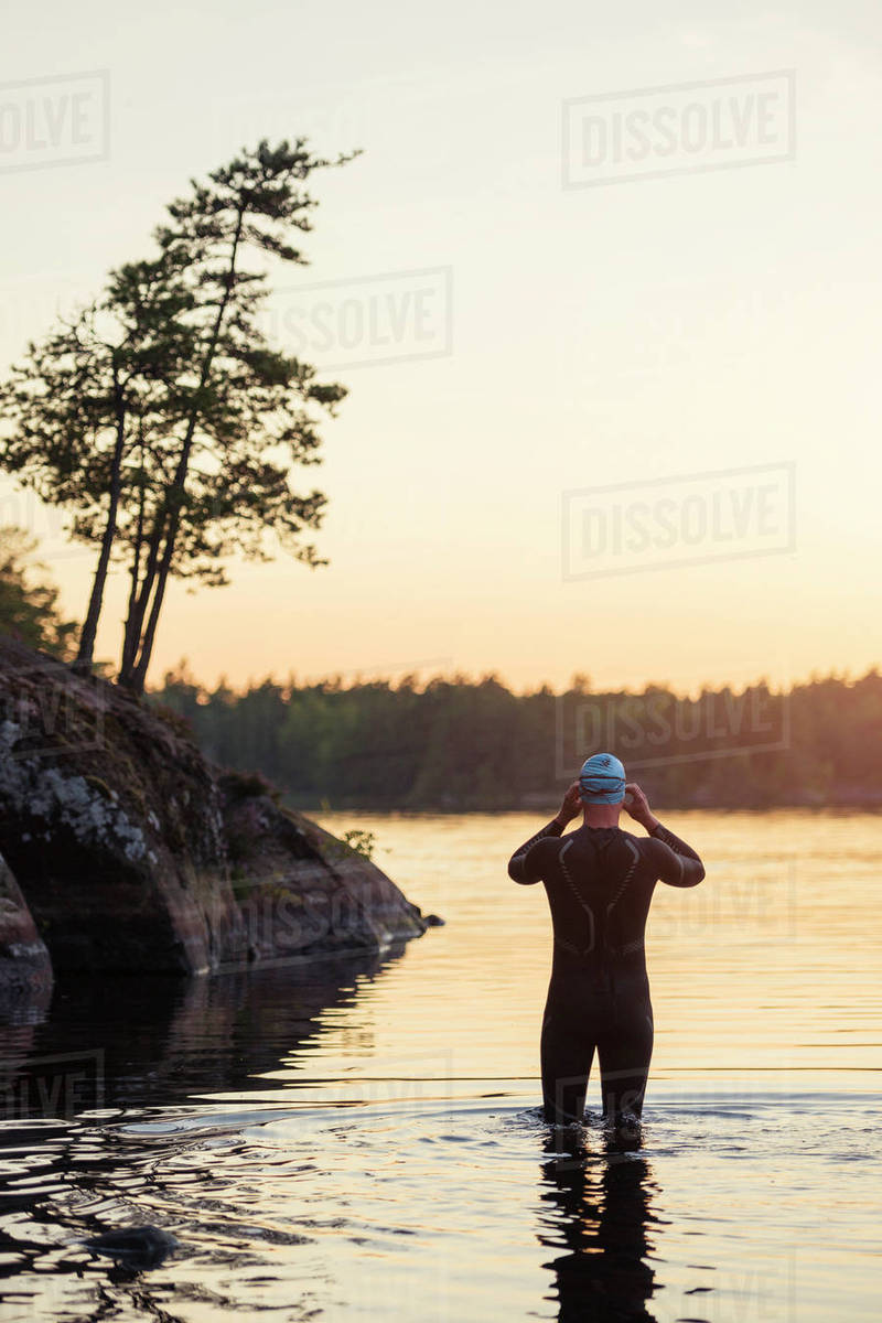 Swimmer standing in water at sunset - Royalty-free Stock Photo | Dissolve