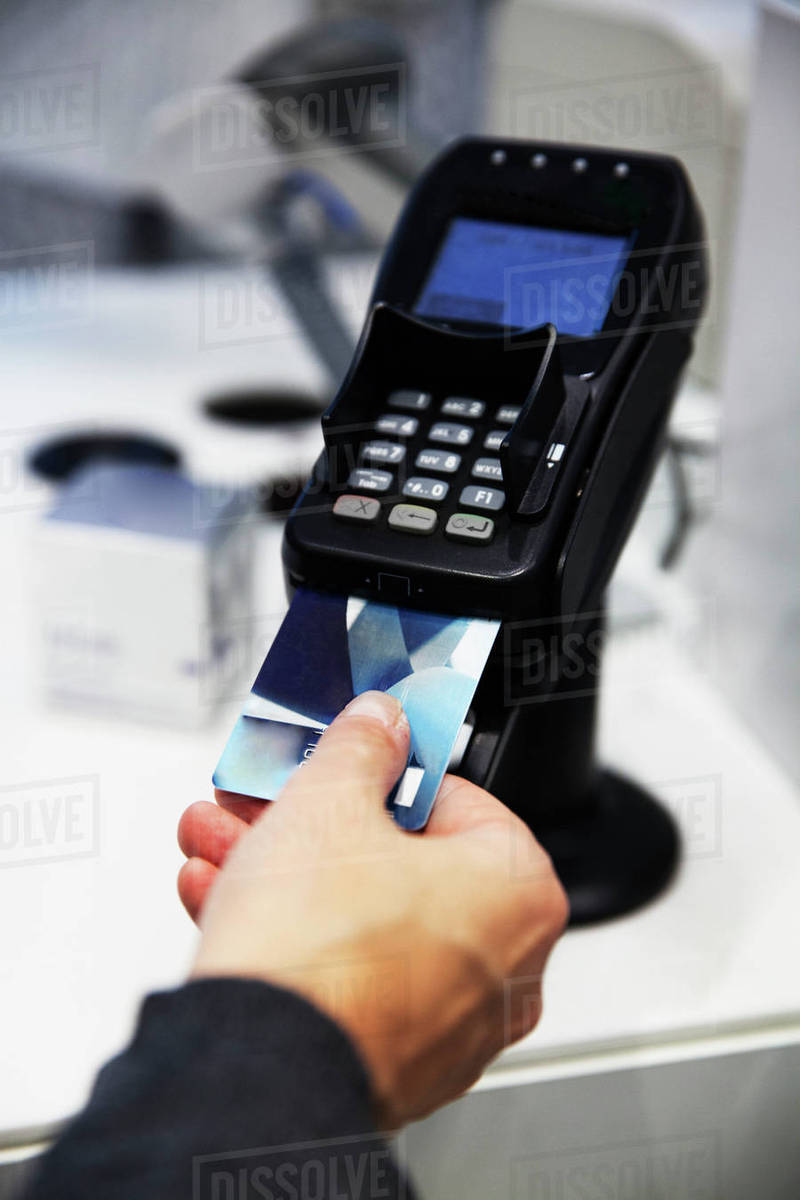 Hand putting bank card into card reader - Stock Photo - Dissolve