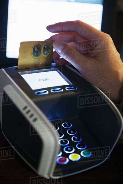 Hand putting bank card into card reader - Stock Photo - Dissolve