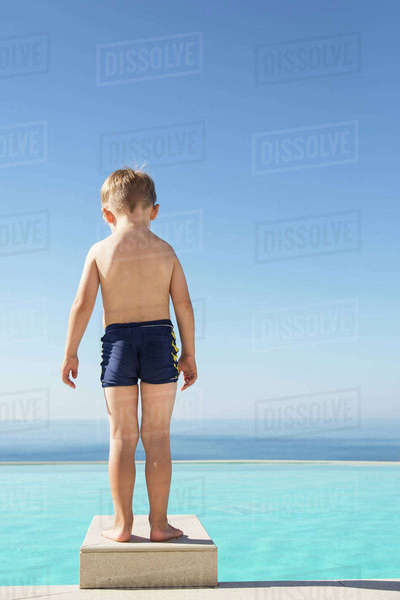Boy standing on edge of swimming-pool - Royalty-free Stock Photo | Dissolve