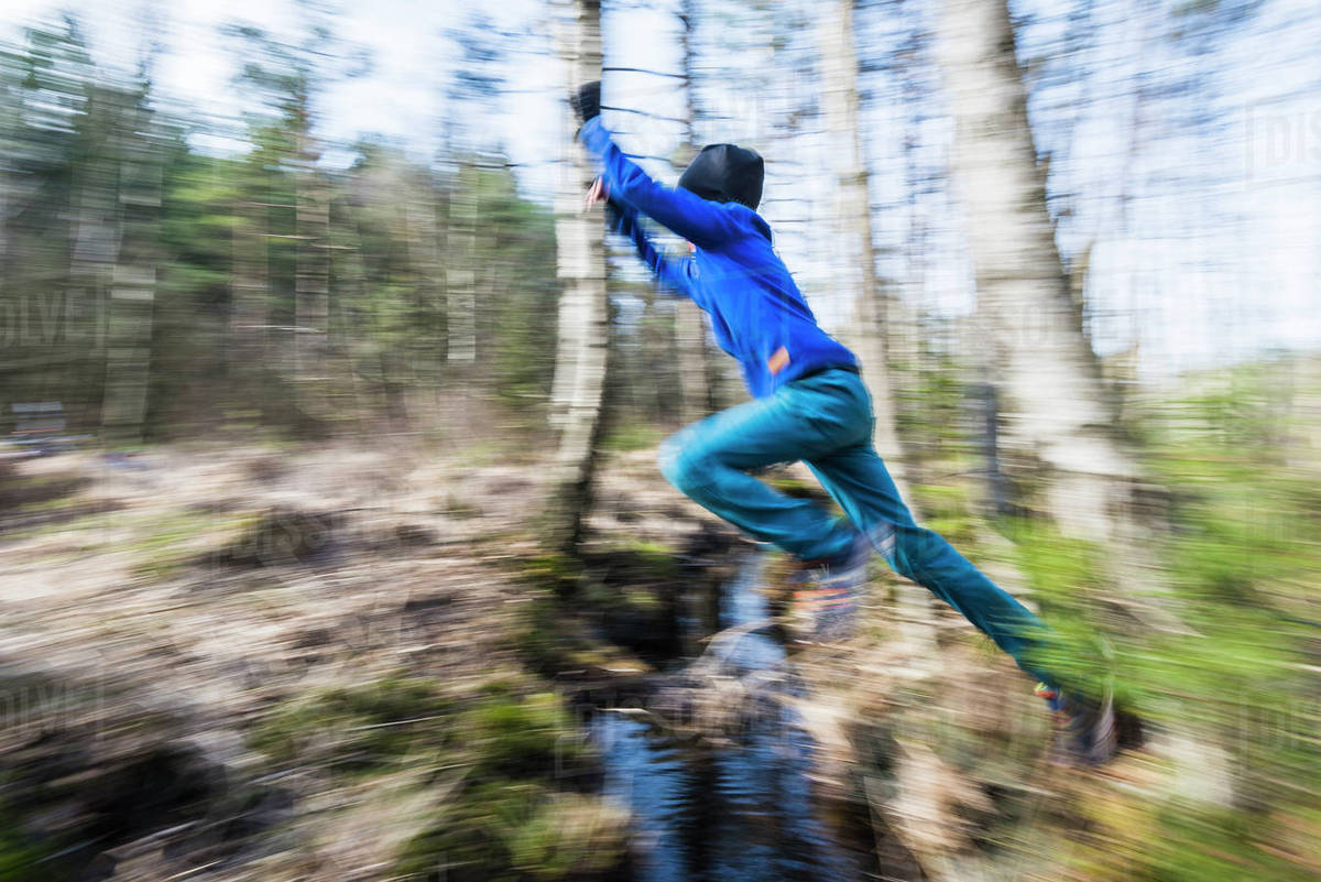 Boy jumping through stream - Stock Photo - Dissolve