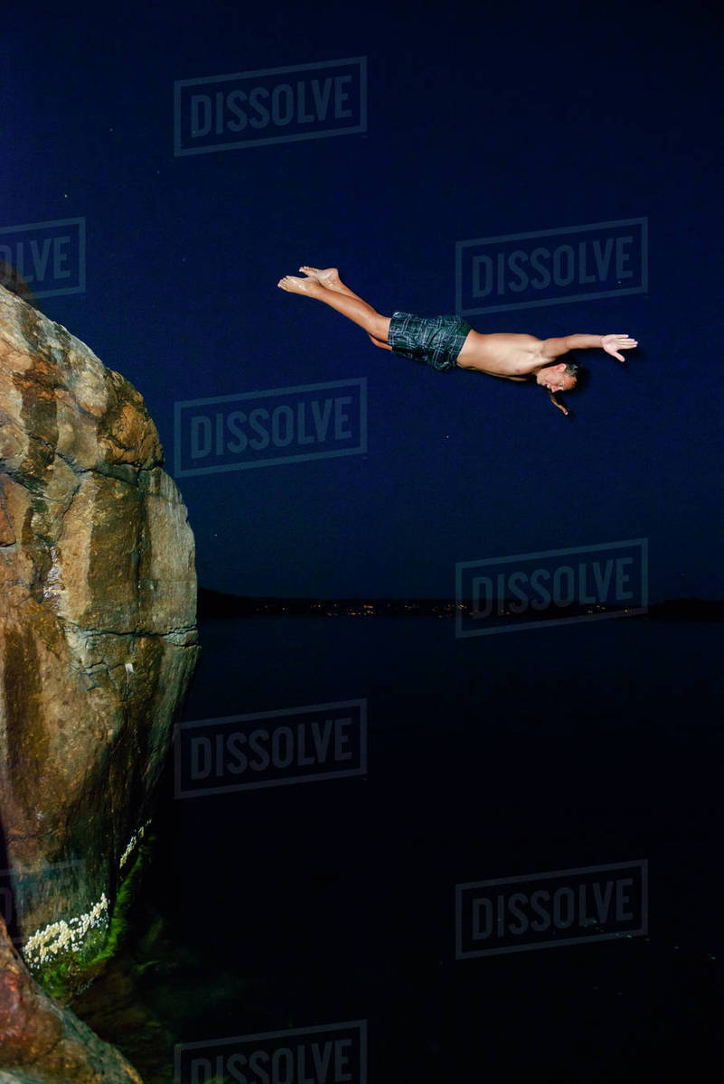 Man jumping into sea at night - Stock Photo - Dissolve