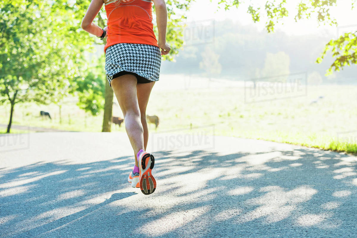 Woman jogging on country road - Royalty-free Stock Photo | Dissolve
