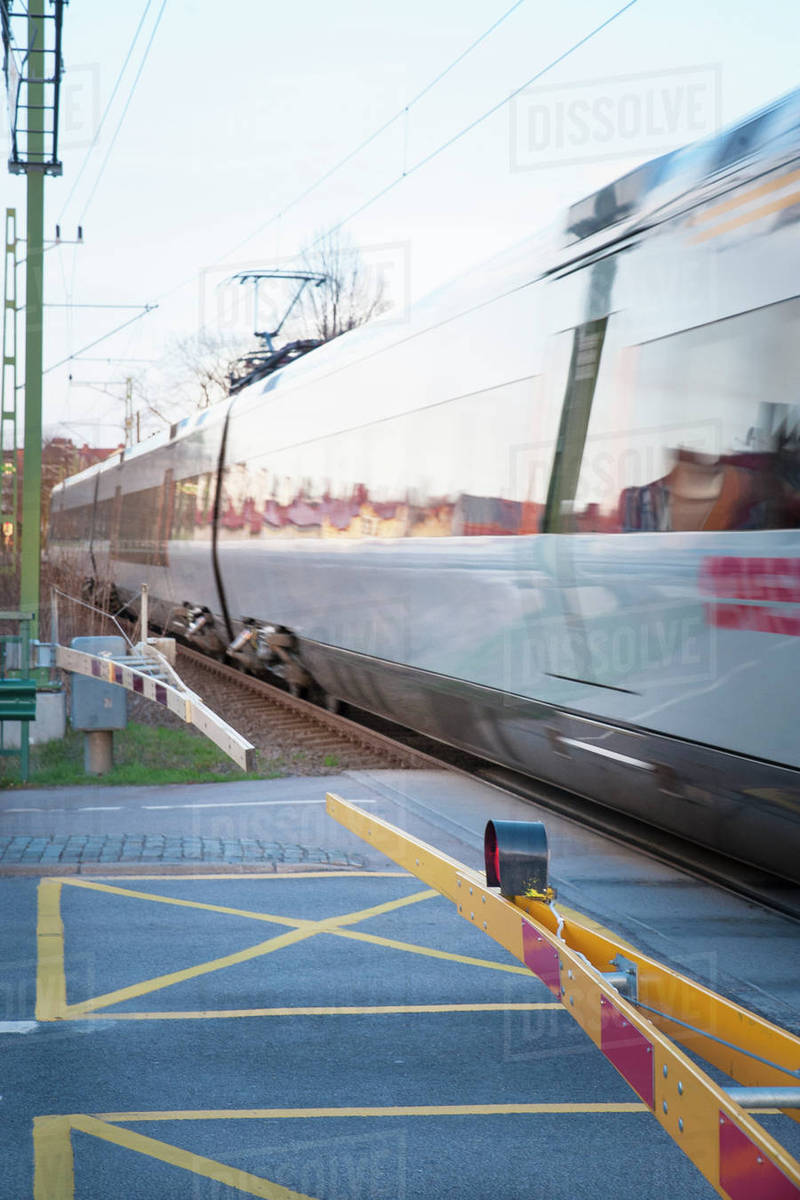 Train driving through railroad crossing - Stock Photo - Dissolve