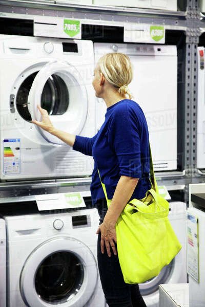 Woman looking at washing machine in shop - Stock Photo - Dissolve