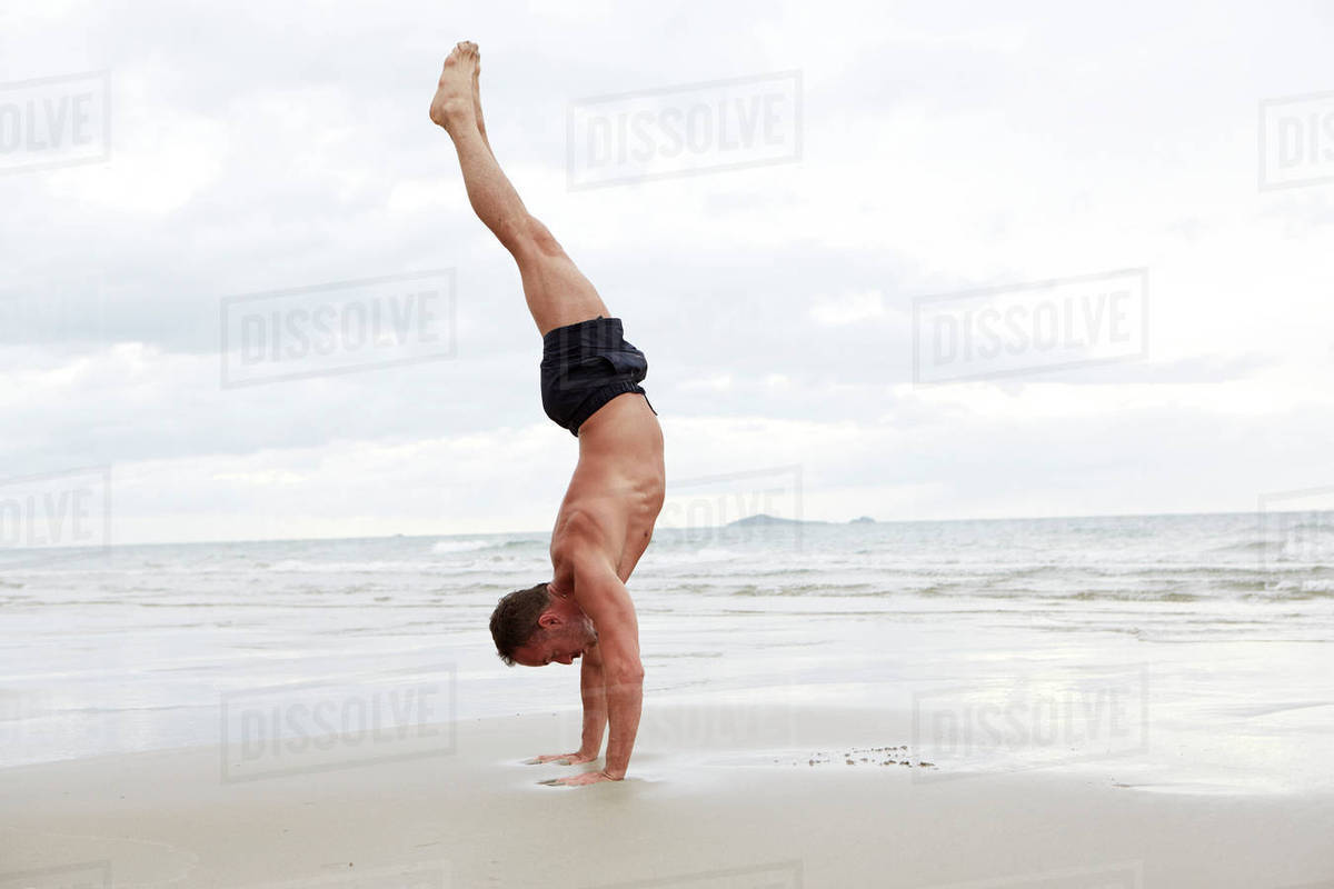 Man doing handstand on beach - Royalty-free Stock Photo | Dissolve