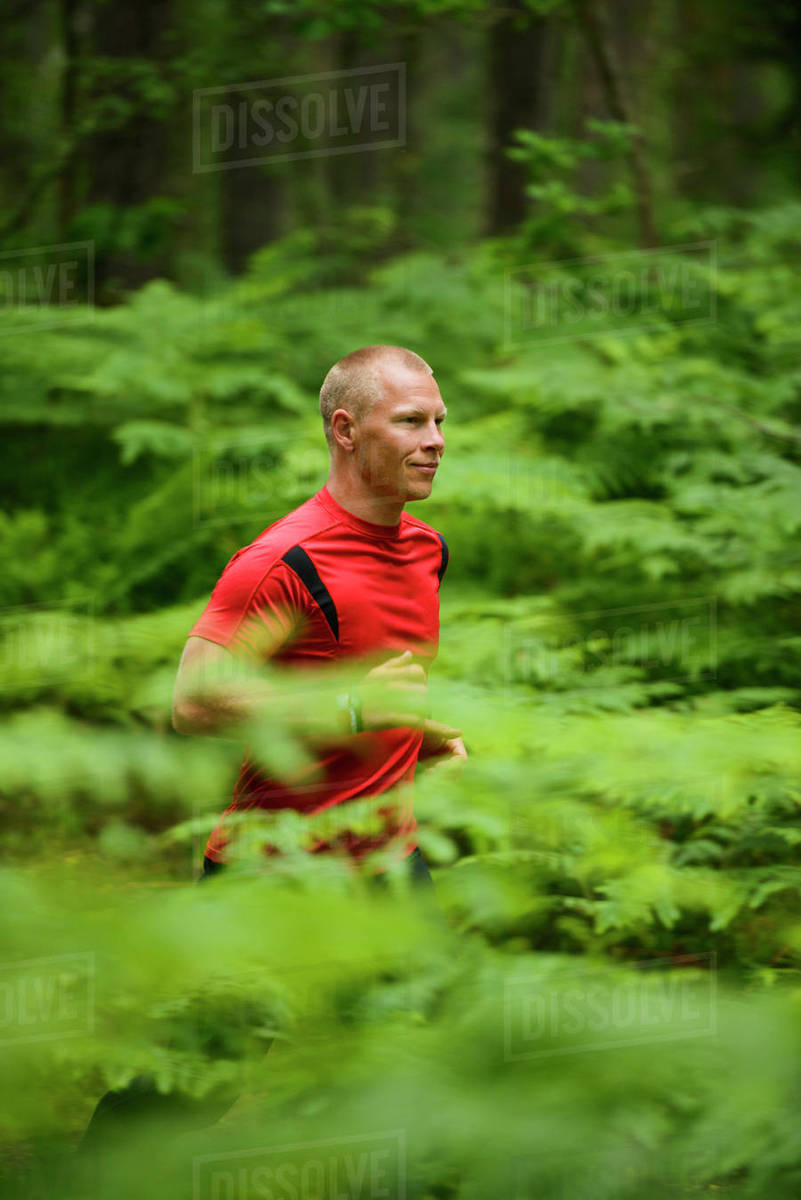 Young man running through forest - Royalty-free Stock Photo | Dissolve