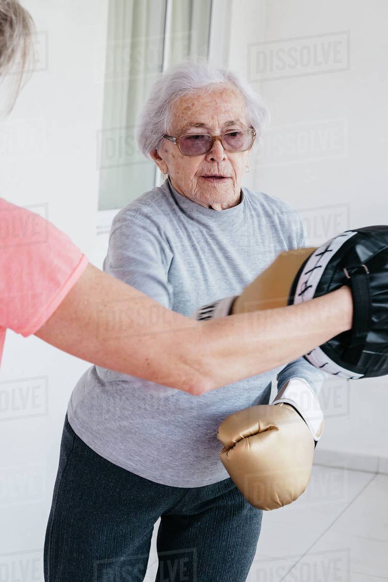 Senior woman boxing with fitness instructor - Stock Photo - Dissolve