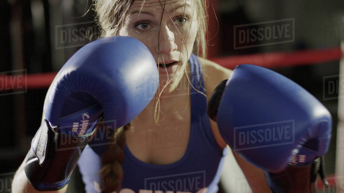 Close up of female boxer in boxing gloves standing in boxing ring ...