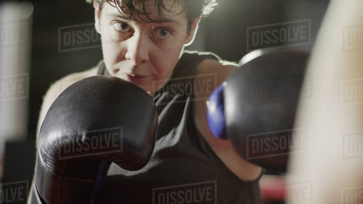 Close up of female boxer in boxing gloves standing in boxing ring ...