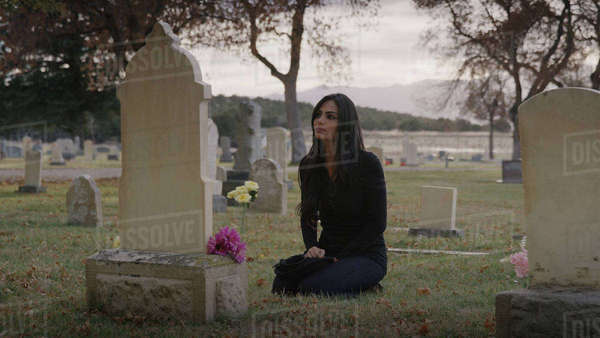 Sad pensive woman sitting at grave in lonely cemetery - Royalty-free ...