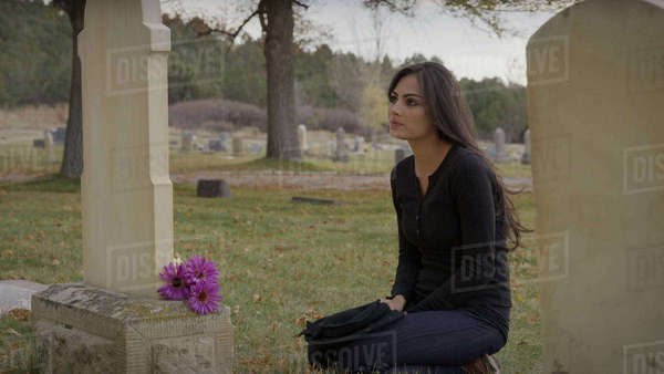 Sad pensive woman sitting at grave in lonely cemetery - Royalty-free ...