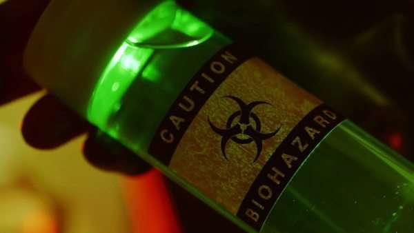 A large vial of green luminescent liquid is labeled as a biohazard ...