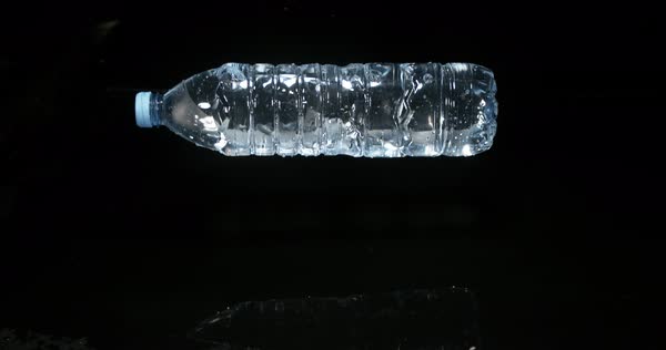 Bottle of water falling on water against black background - Stock Video ...