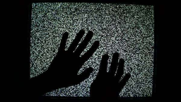 Male hands crawling up the TV screen with static television noise as ...
