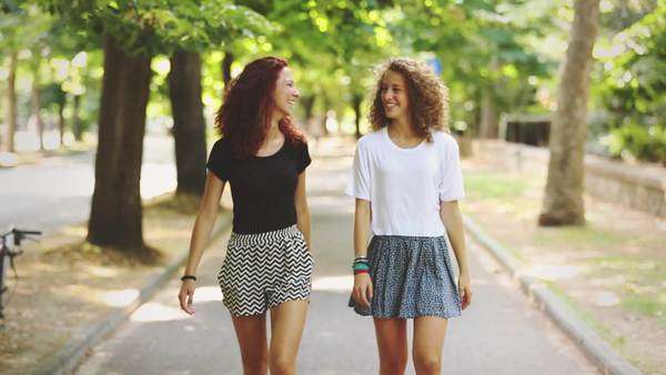 Two beautiful girls walking and laughing in a park, with vintage filter ...