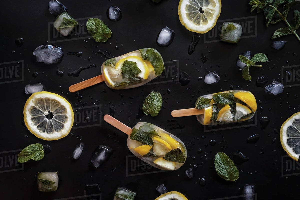 transparent fruit ice on a stick on a dark background with slices of ...