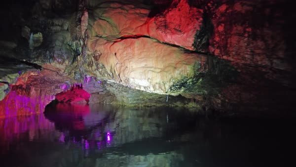 Boating on the underground river in a dark stone cave in magic ...