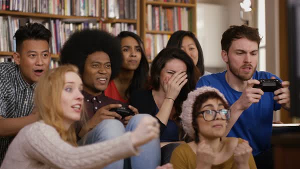 Large group of happy young friends hanging out and playing video games ...