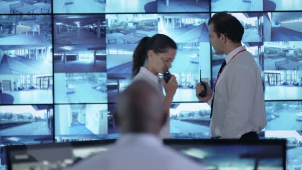 Surveillance team watching CCTV on multiple screens and reacting to ...