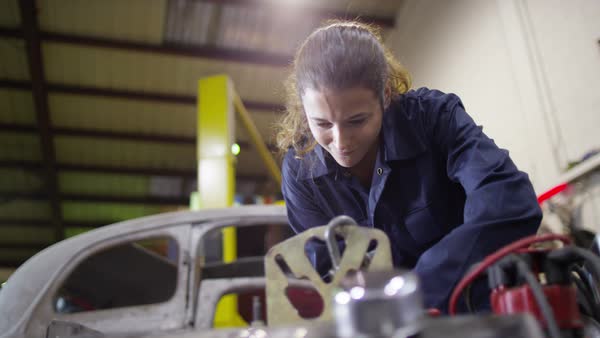 Attractive female mechanic working on car engine in garage workshop ...