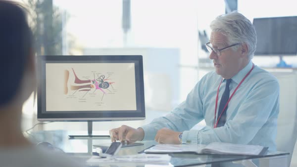 Audiology doctor showing patient a modern hi tech hearing aid and ...