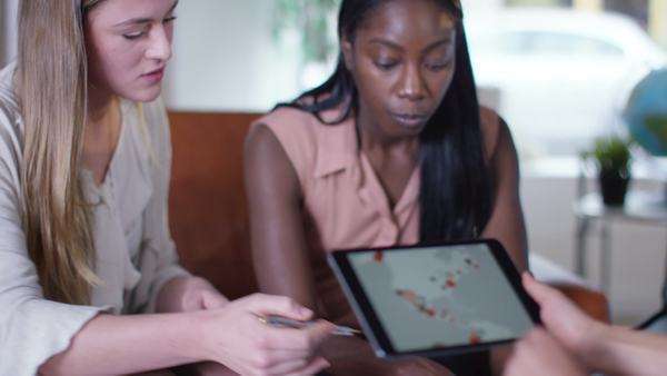 Female business team in a meeting, looking at world map on computer ...