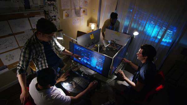 Young creative computer design team working together in dark office ...