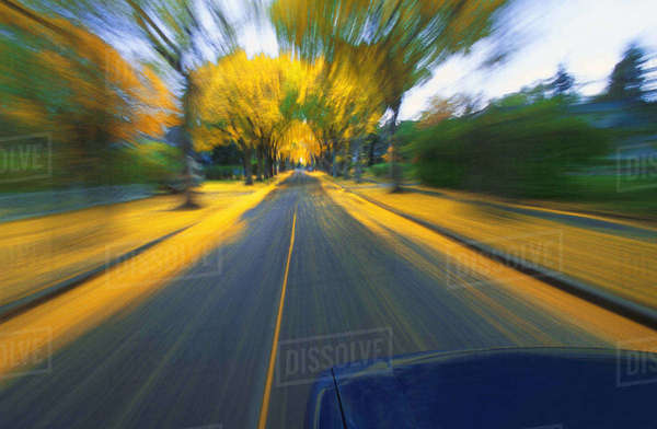 Speeding Down A Road In Autumn - Stock Photo - Dissolve