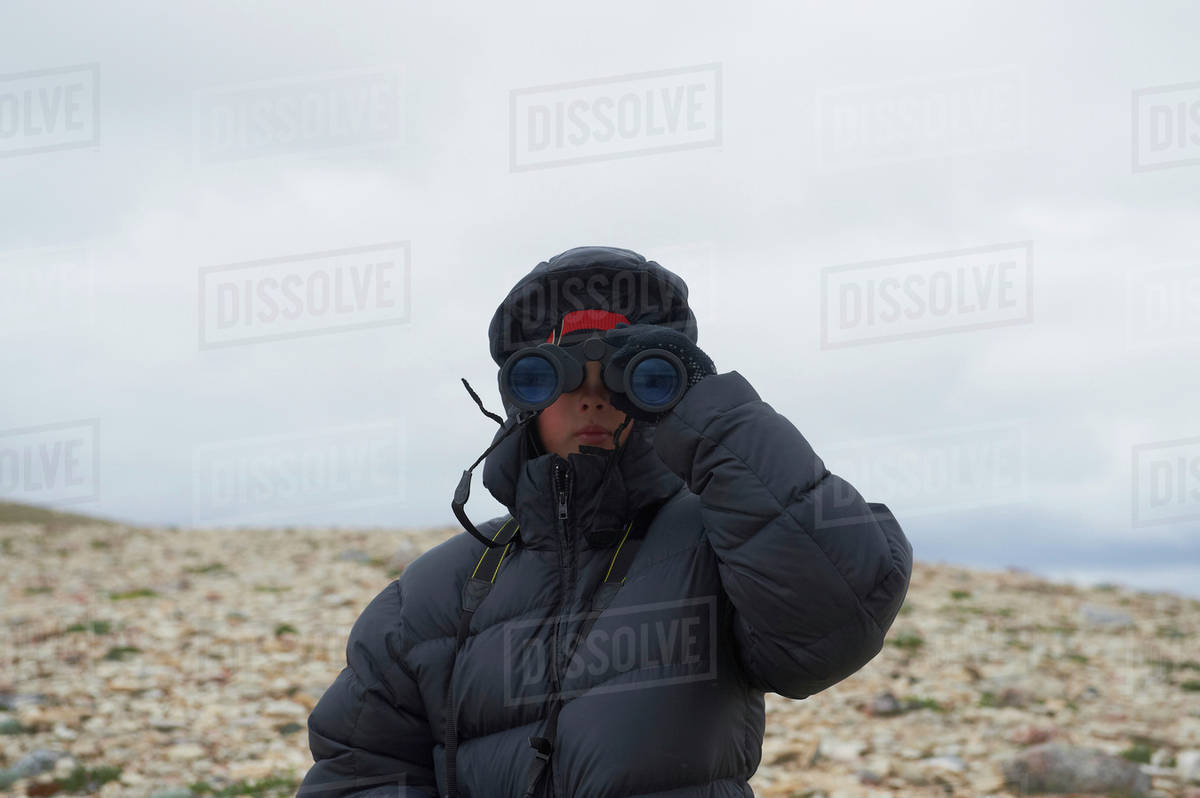 Teenager looking through binoculars on Mount Pelly, Ovayok Territorial ...