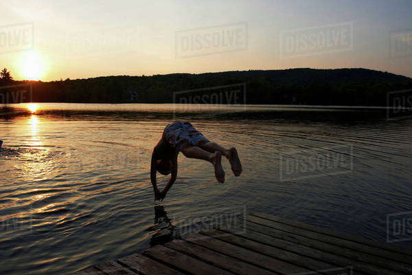 Boy diving into a lake at sunset; Lac des Neiges, Quebec, Canada ...