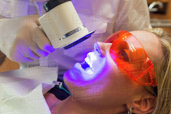 Dentist using fluorescence visualization to check for oral diseases ...