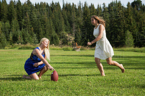 Two girlfriends playing football in a park in their dresses; Edmonton ...