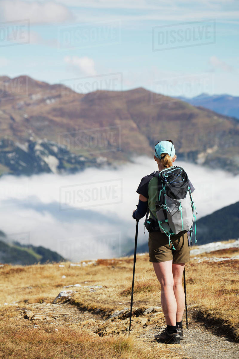 Female hiker on trail overlooking a cloud covered valley and mountain ...