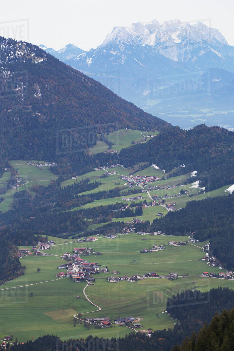 View of an alpine village with green meadows, rolling hills and trees ...