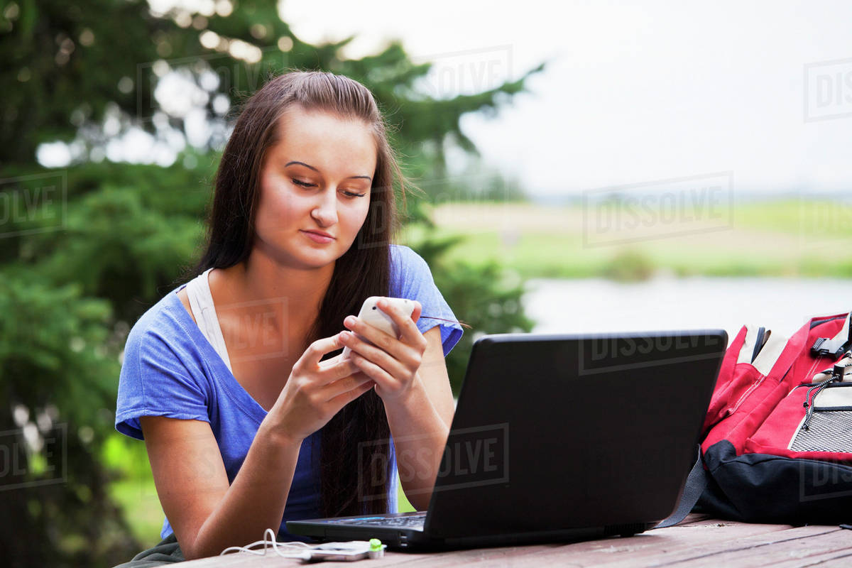 Student checking for text messages while studying outdoors using a ...