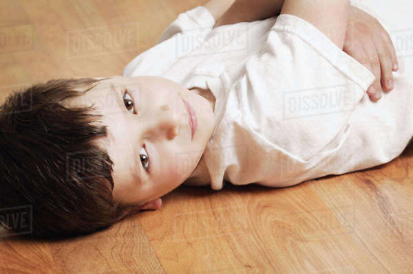 Boy Laying On Hardwood Floor - Stock Photo - Dissolve