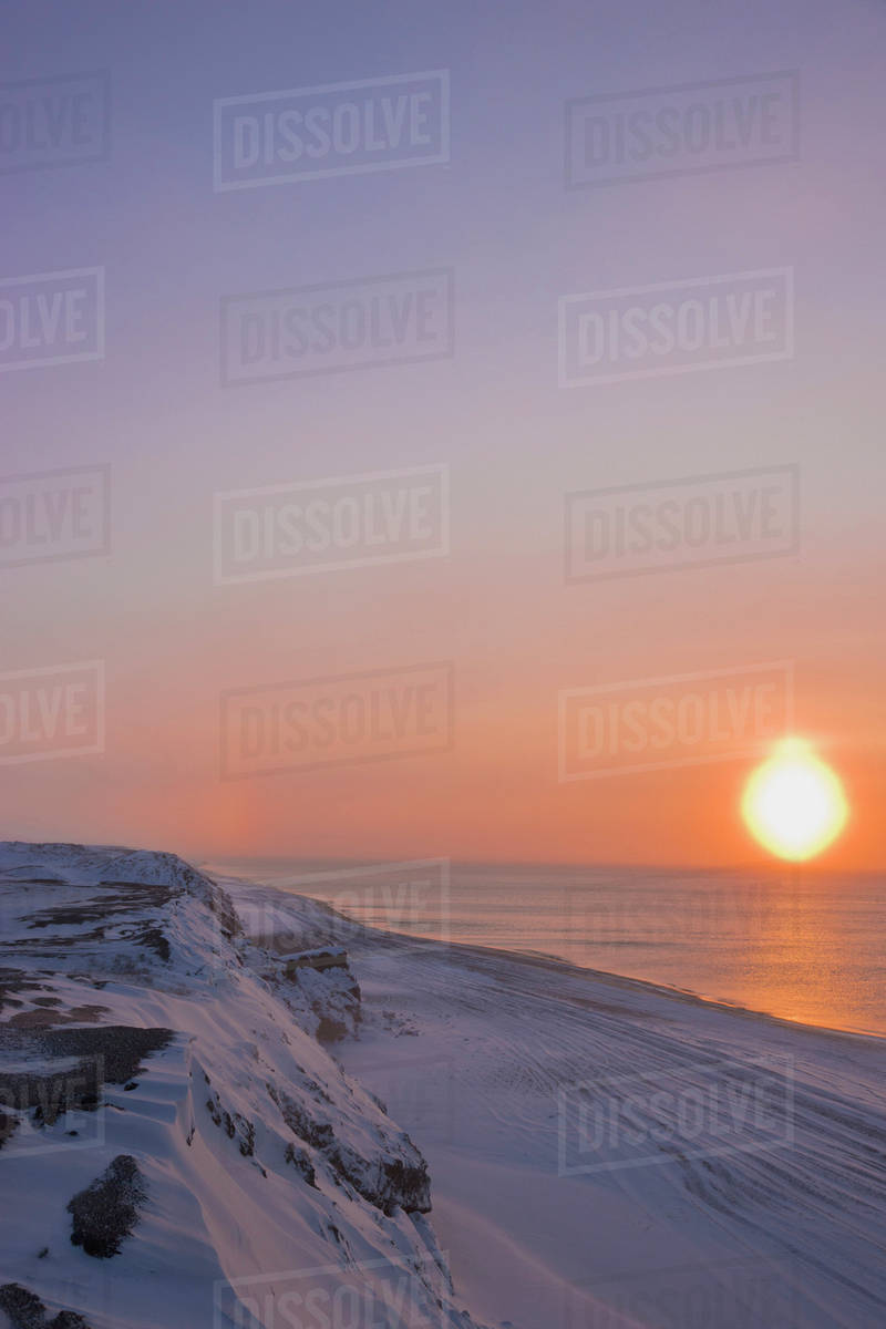 Sunset through windblown snow creates a sundog above the Beaufort Sea ...
