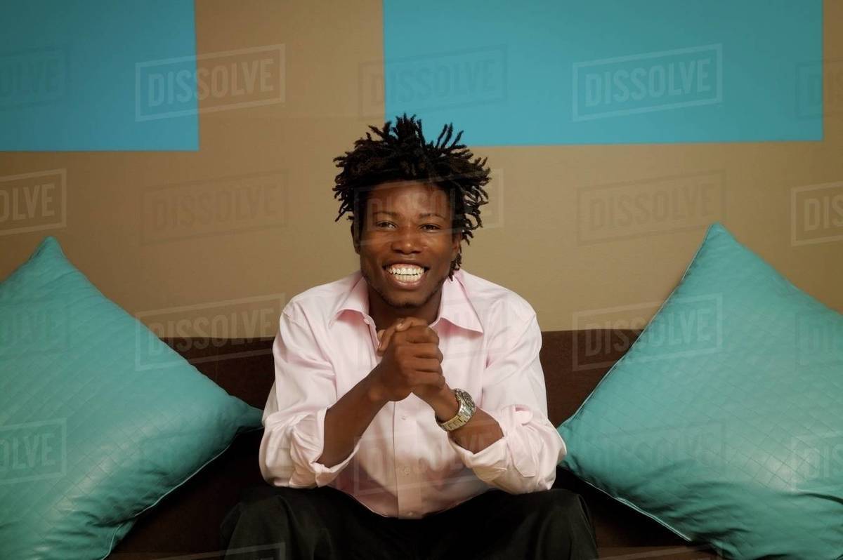Man Sitting On Couch Smiling - Royalty-free Stock Photo | Dissolve