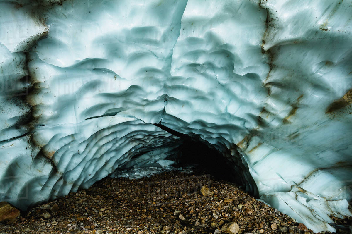 An ice cave with a scalloped ice ceiling and a floor of glacial till ...