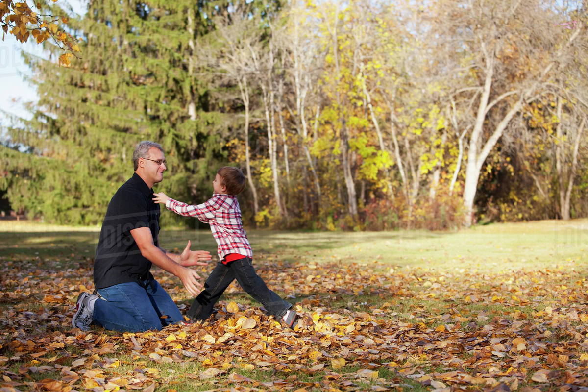Grandfather and grandson playing in a park in autumn;Edmonton, alberta ...