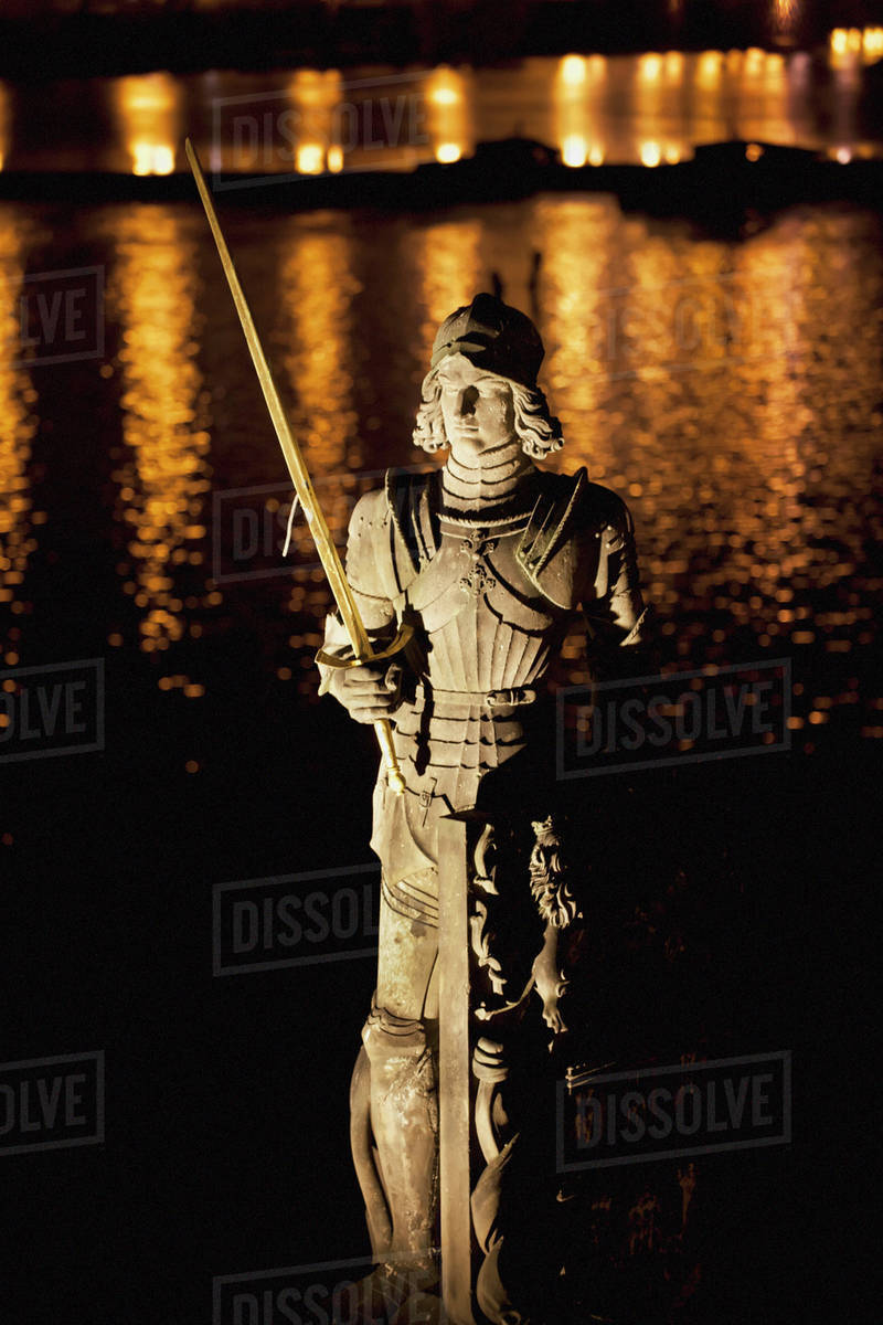 Statue illuminated by light with light reflecting on the water in the ...