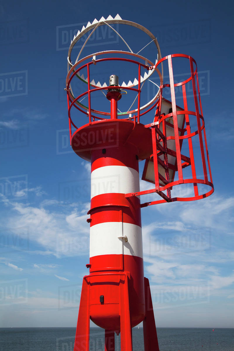 A red and white beacon at the water's edge;Vlissingen, zealand ...