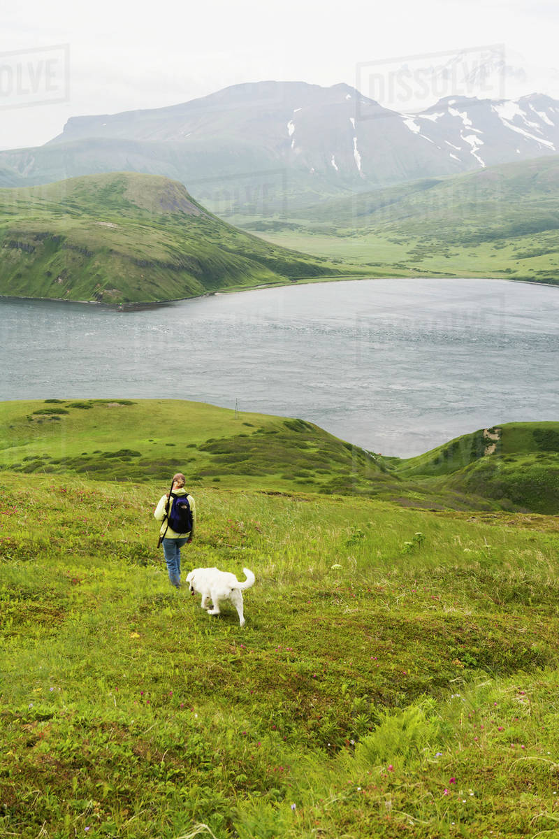 A Woman Hiking With Her Dog And Enjoying The View Of Isanotski Strait ...