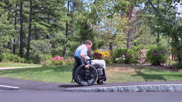 Man with spinal cord injury in a wheelchair using accessible street to ...