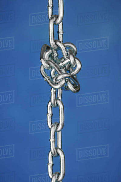 A chain tied in a knot against a blue background - Stock Photo - Dissolve
