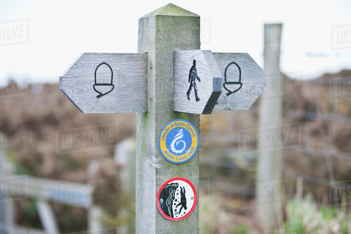 A wooden post and directional signs for walking paths;Wales - Royalty ...